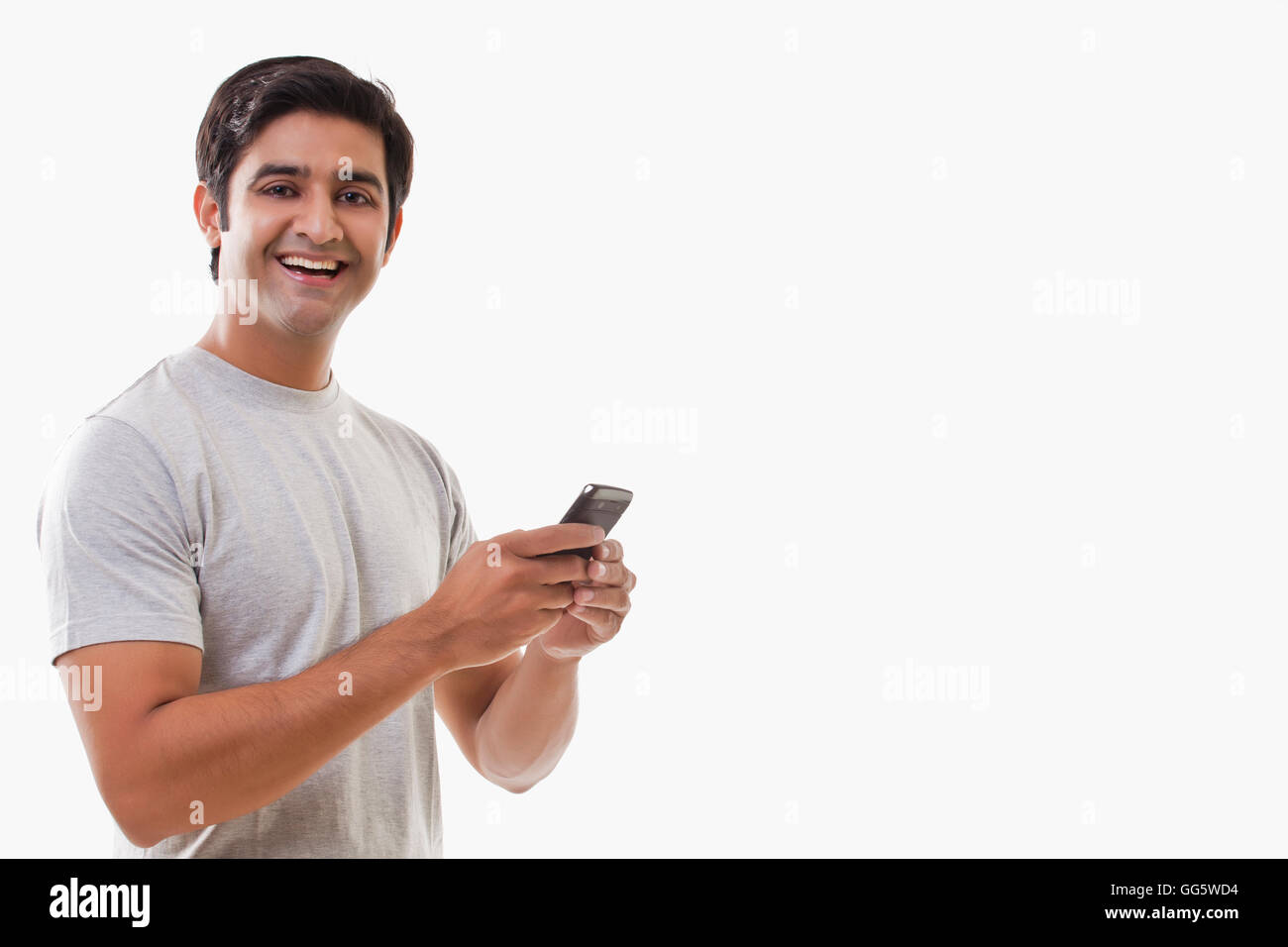Cheerful young man holding cell phone over white background Stock Photo ...