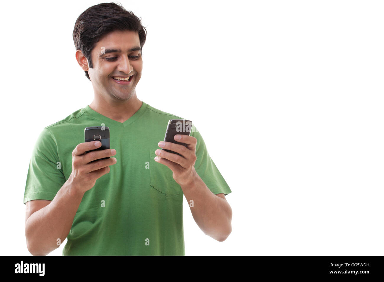 Smiling young man text messaging through cell phones Stock Photo - Alamy