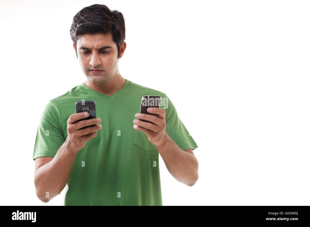 Serious young man text messaging over white background Stock Photo - Alamy