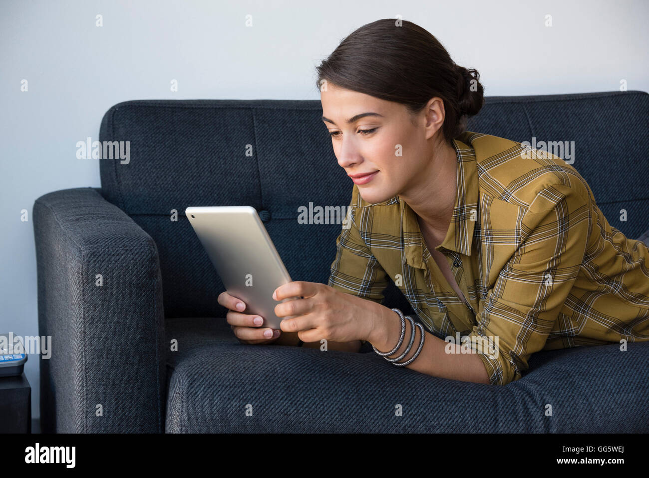 Young beautiful woman using a digital tablet on couch Stock Photo - Alamy