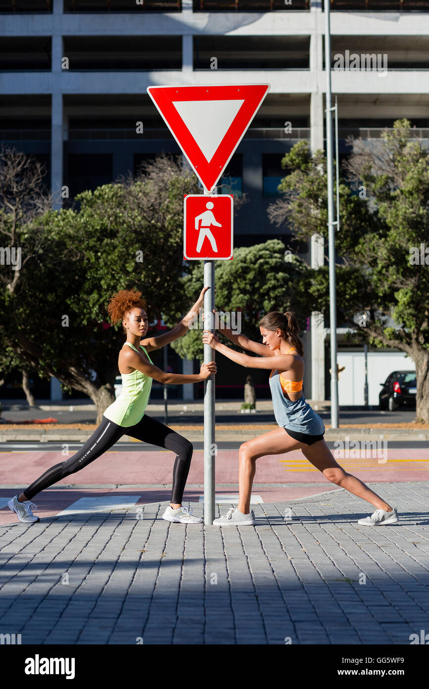 Young female athletes doing stretching exercise by pole on street Stock ...