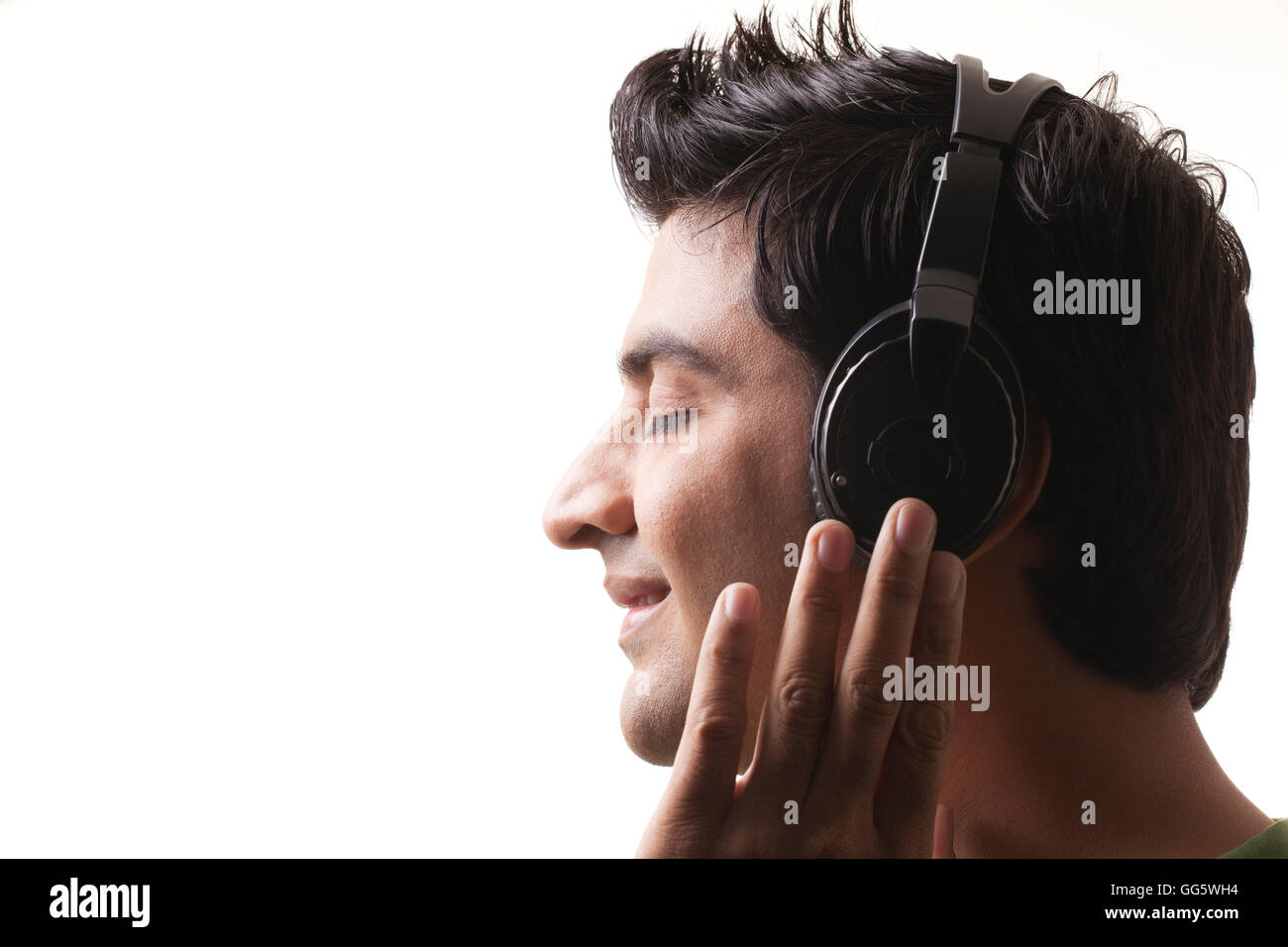 Smiling young man enjoying music over white background Stock Photo - Alamy