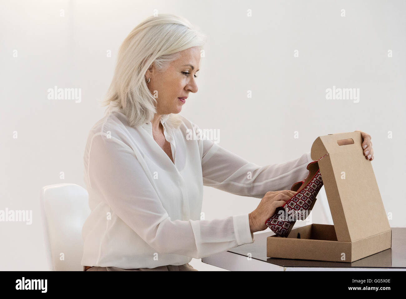 Side profile of a woman opening a parcel of sandal Stock Photo - Alamy