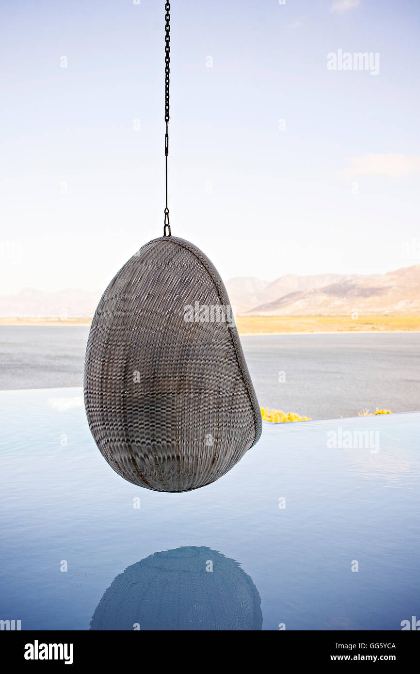 Swing chair hanging on infinity pool in resort Stock Photo - Alamy