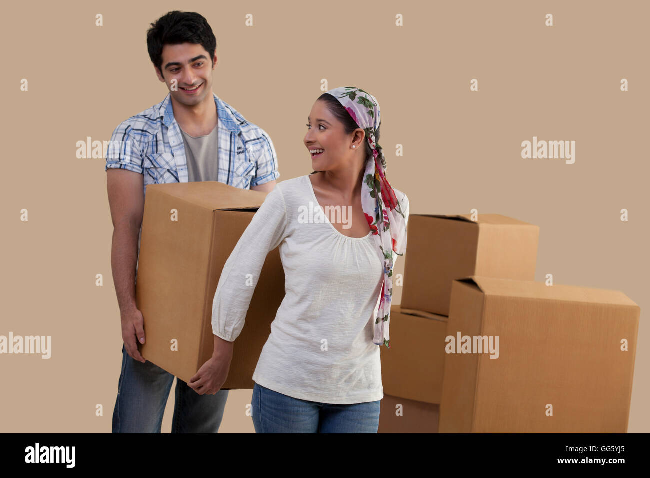 Beautiful young couple carrying cardboard boxes together while moving ...