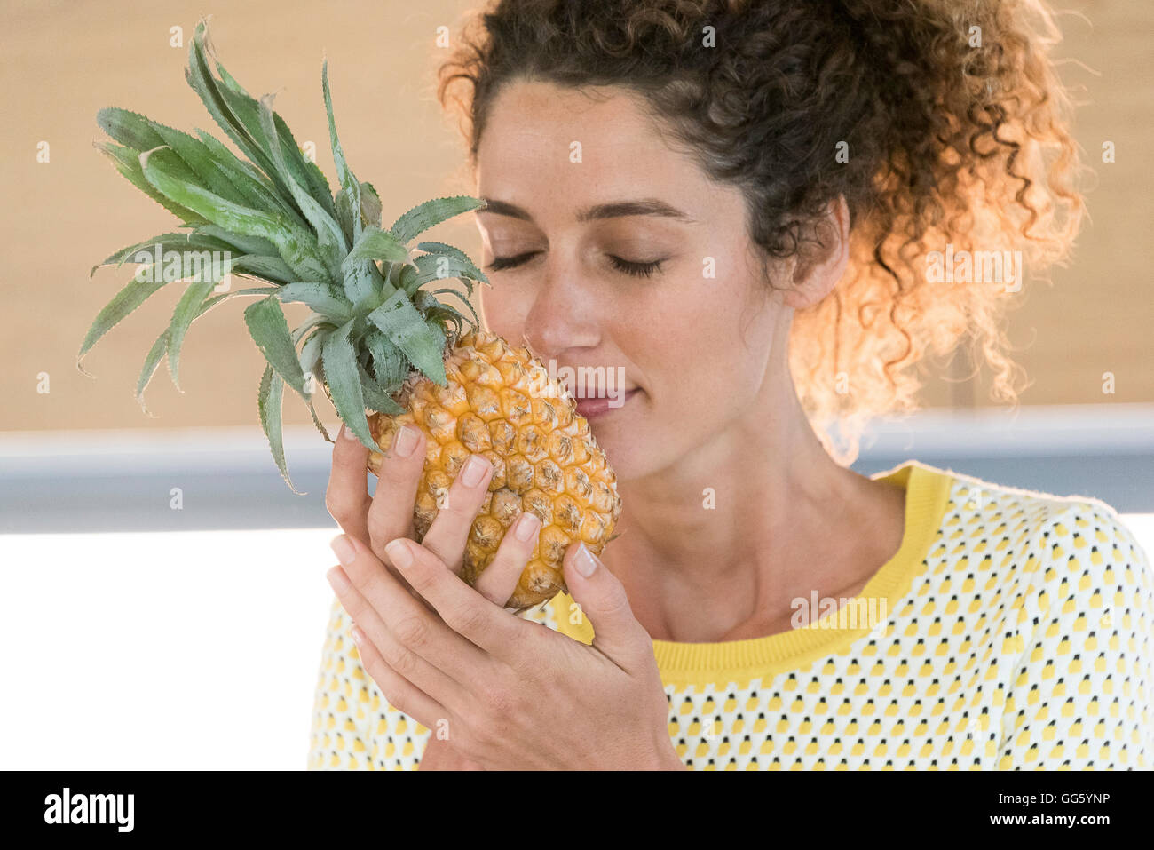 Close-up of a woman smelling a pineapple Stock Photo - Alamy