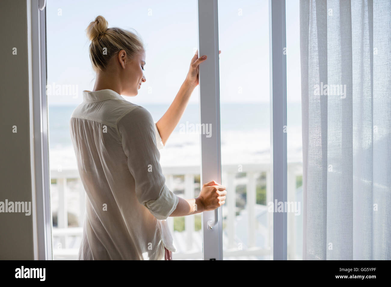 Young woman standing by window at home Stock Photo - Alamy