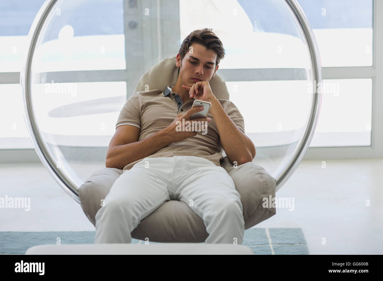 Man sitting in a chair using a smart phone Stock Photo - Alamy