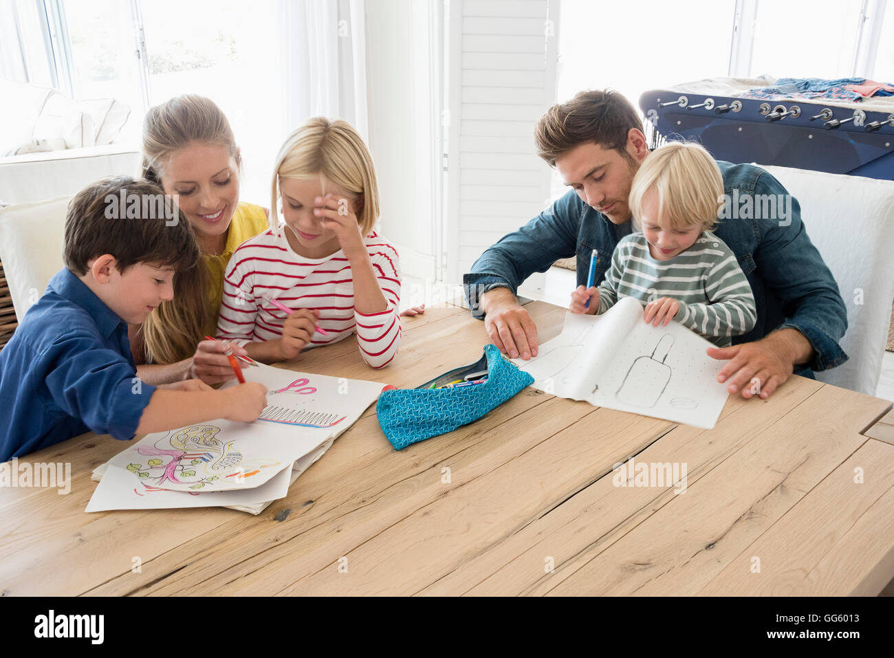 Parents and children doing homework on table Stock Photo - Alamy