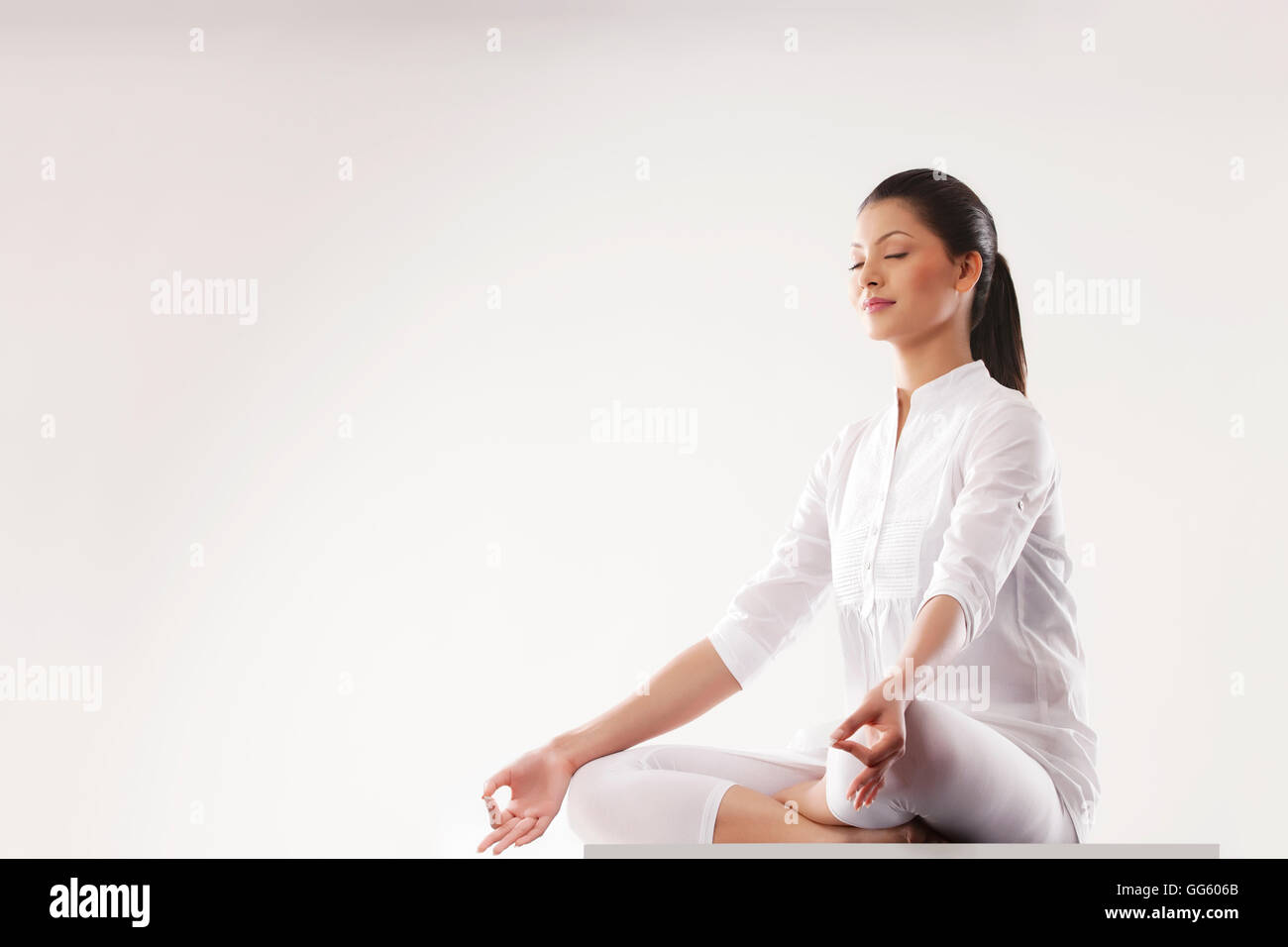 Young woman sitting in lotus position over white background Stock Photo ...