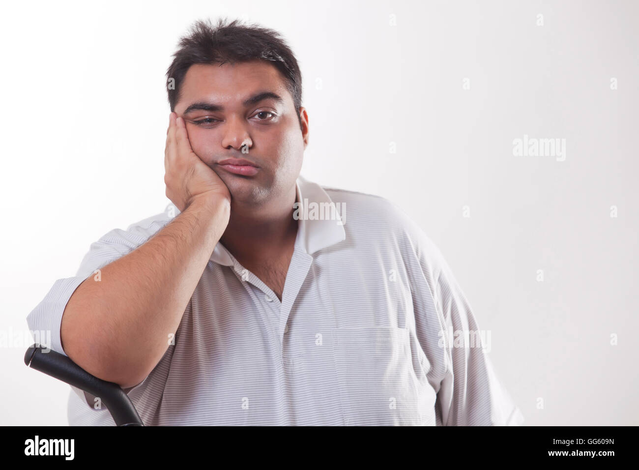 Portrait of a tired obese man with hand on face over white background ...