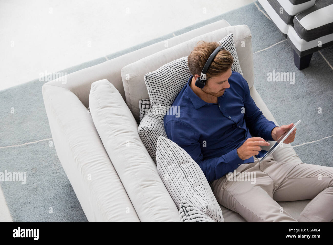 Young man sitting on couch using a digital tablet Stock Photo - Alamy