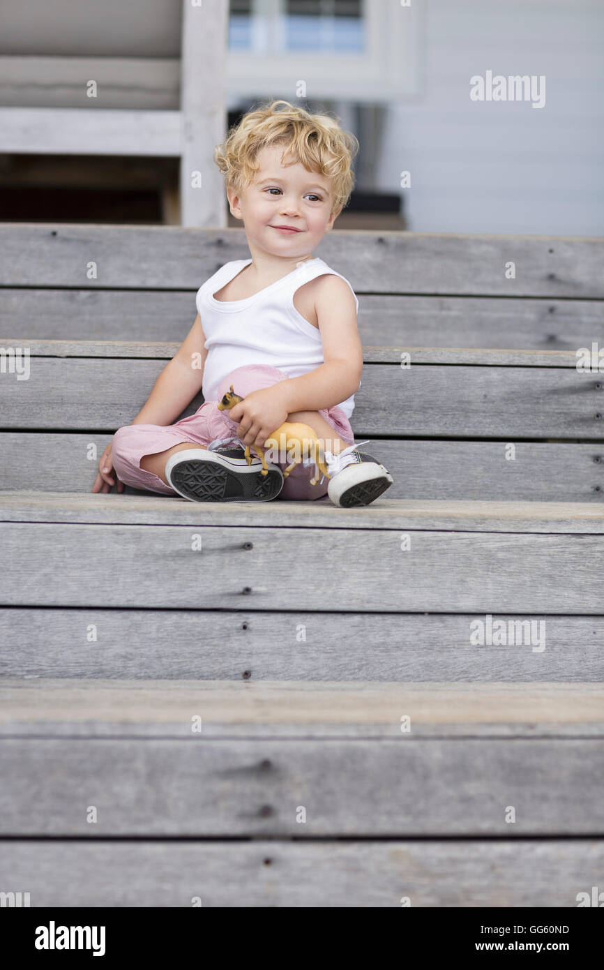Cute baby boy sitting on steps with toy Stock Photo - Alamy