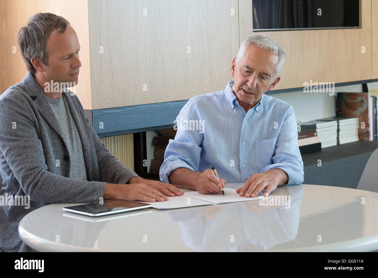 Senior man doing paperwork with financial advisor at home Stock Photo ...