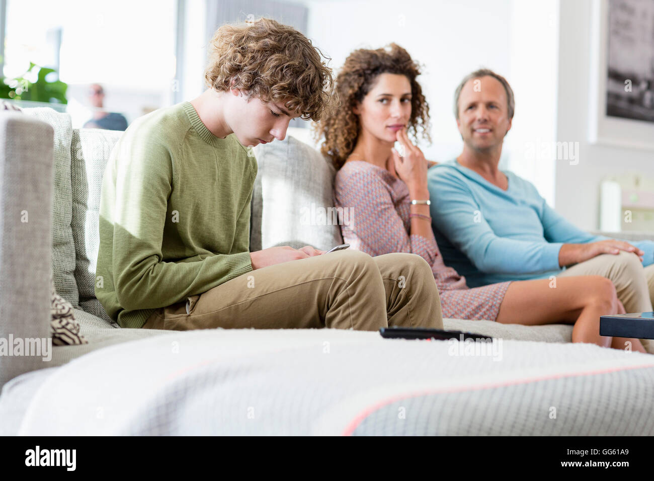 Happy family sitting in a living room at home Stock Photo - Alamy