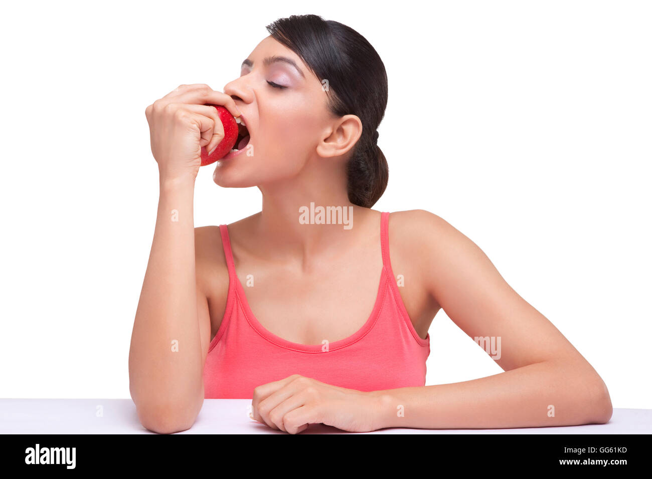 Young woman taking a bite of fully ripped apple over white background ...