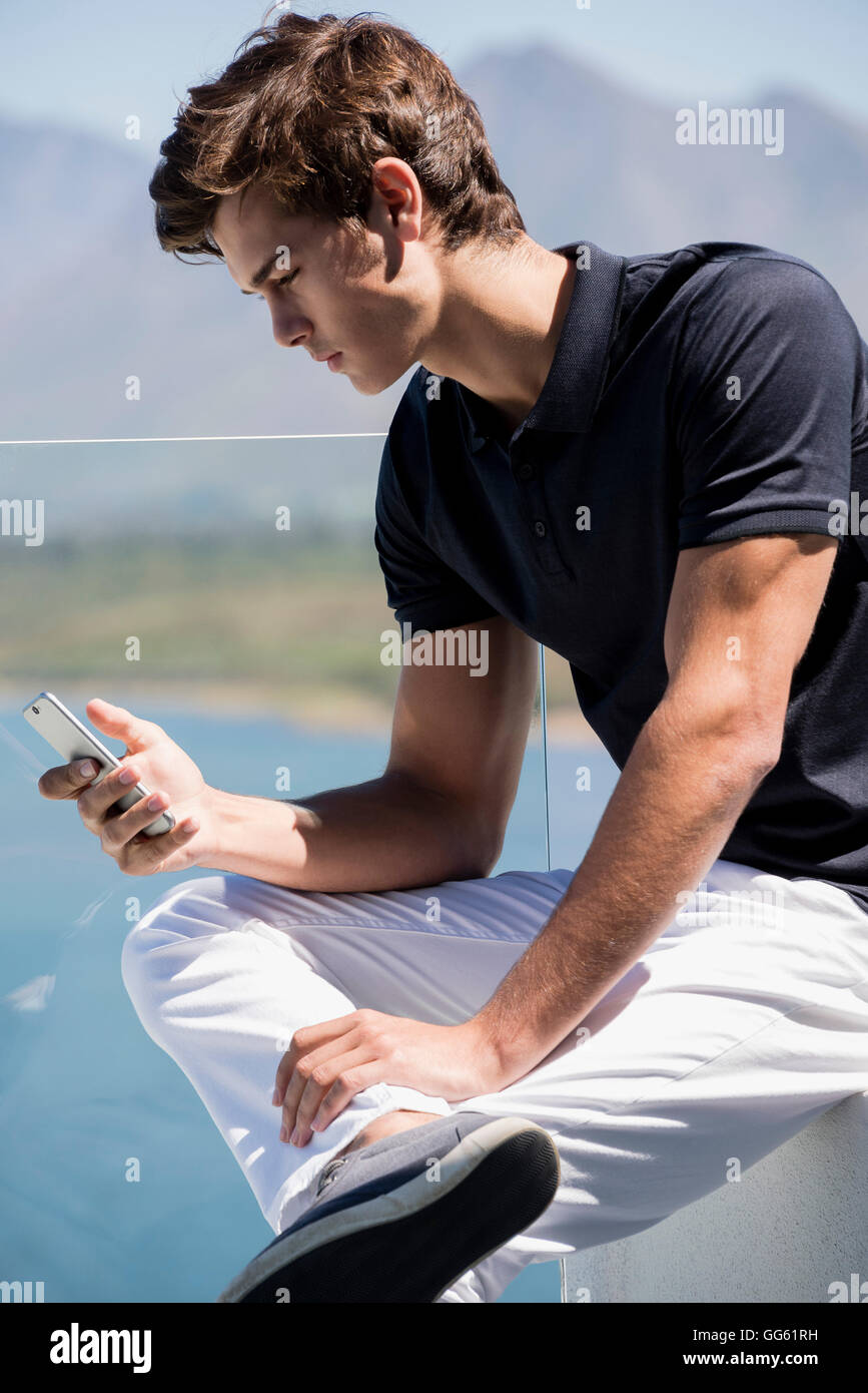 Young man using a phone on balcony outdoors Stock Photo - Alamy