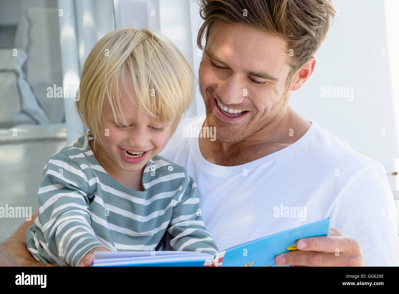 Happy father and son reading a book Stock Photo - Alamy