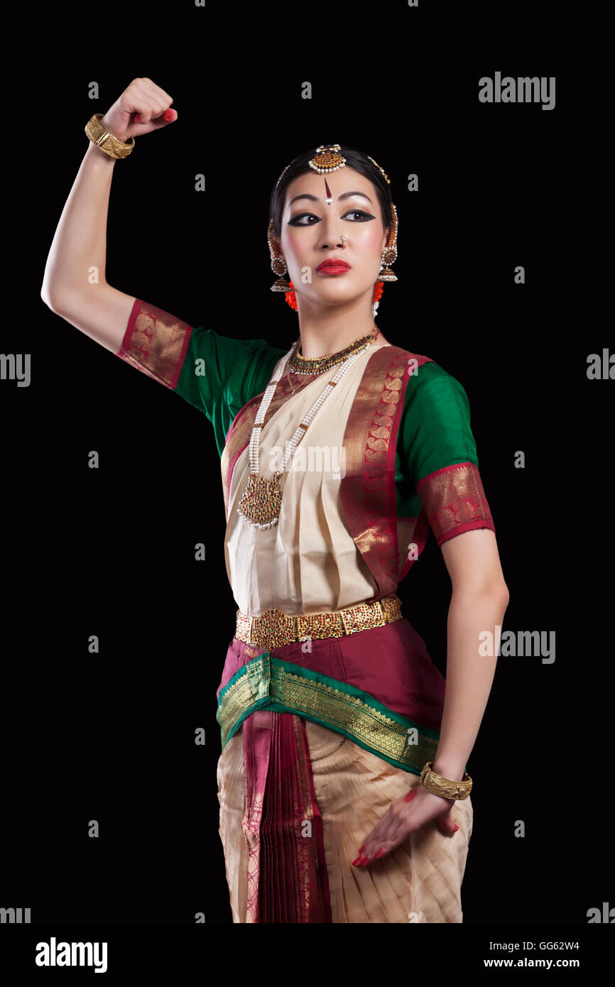 Confident Bharatanatyam dancer flexing muscle over black background ...