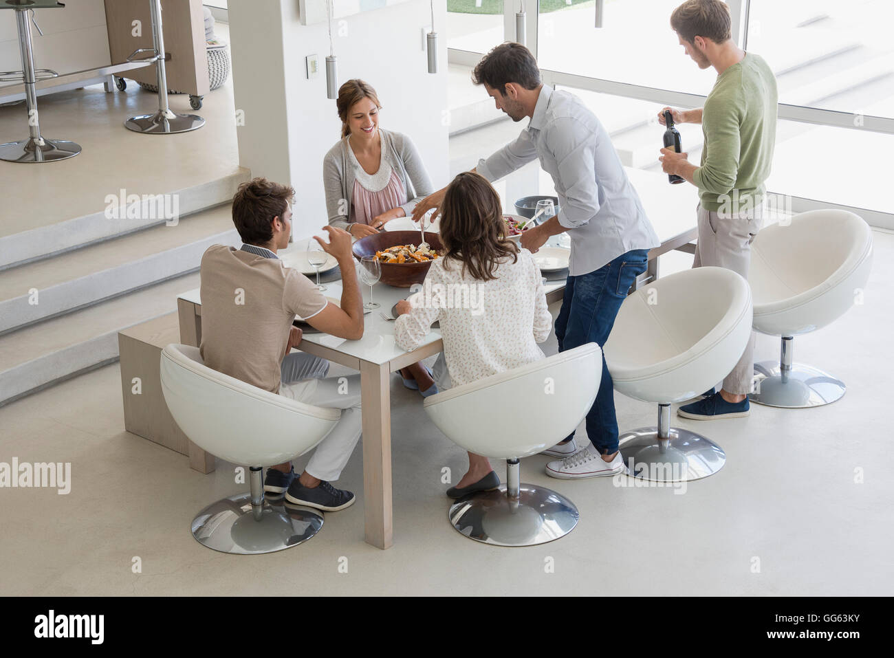 Man serving food to his friends at dining table Stock Photo - Alamy