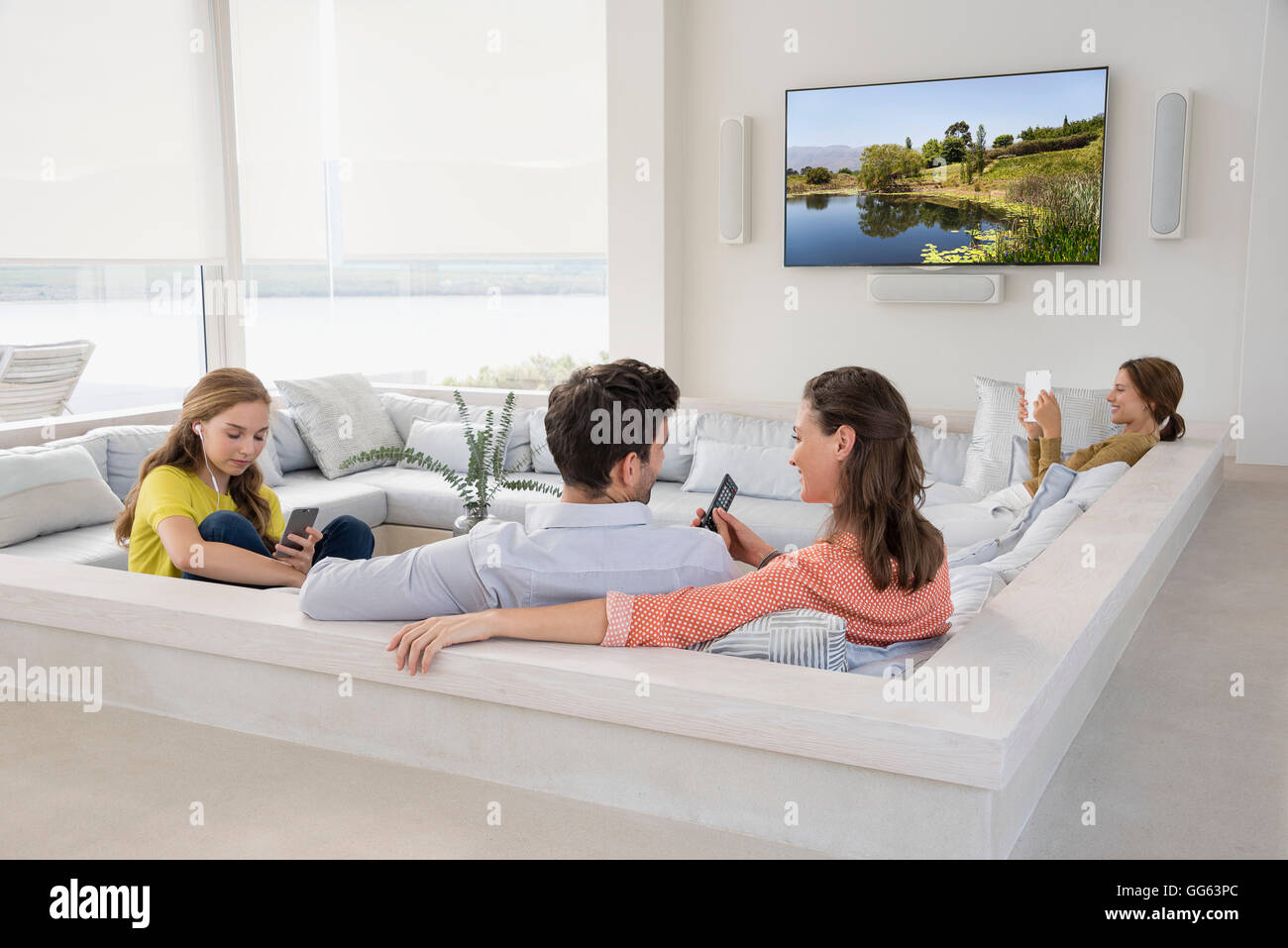 Couple watching television with their children busy in different ...