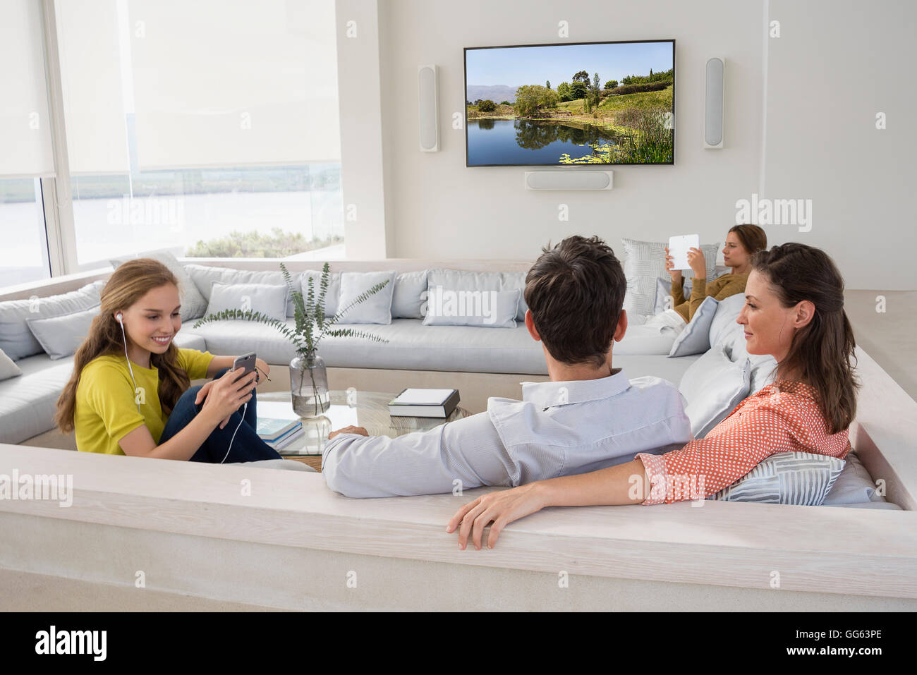 Couple watching television with their children busy in different ...