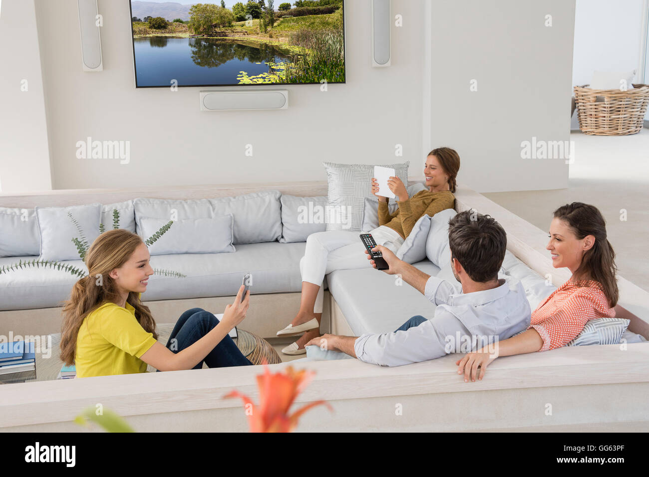 Couple watching television with their daughters busy in different ...