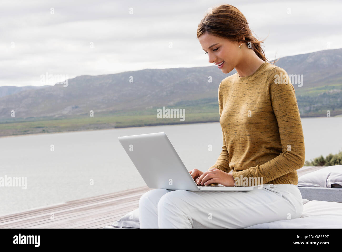 Pretty young woman using a laptop at lakeshore Stock Photo - Alamy