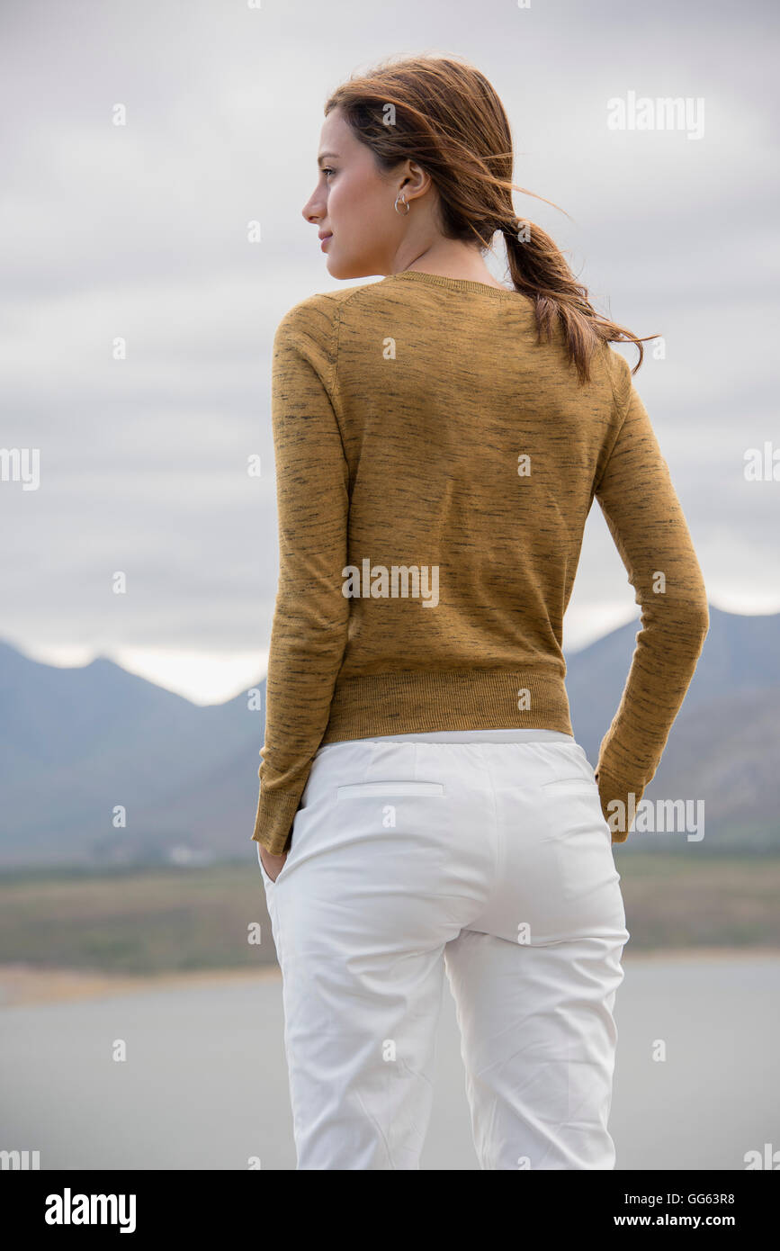 Rear view of a woman standing at lakeshore looking at view Stock Photo ...