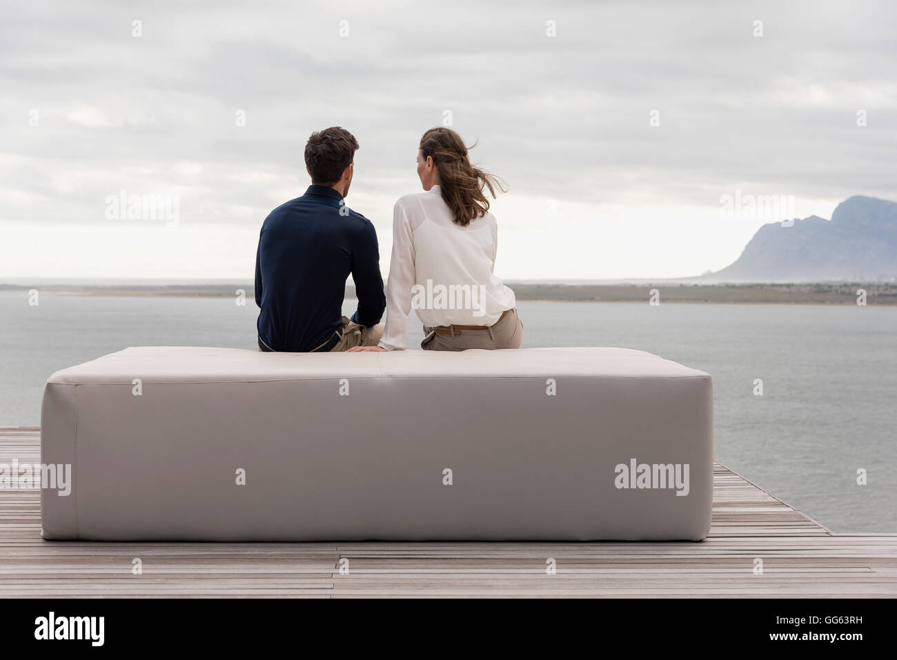Rear view of a couple sitting on ottoman looking at a view Stock Photo ...