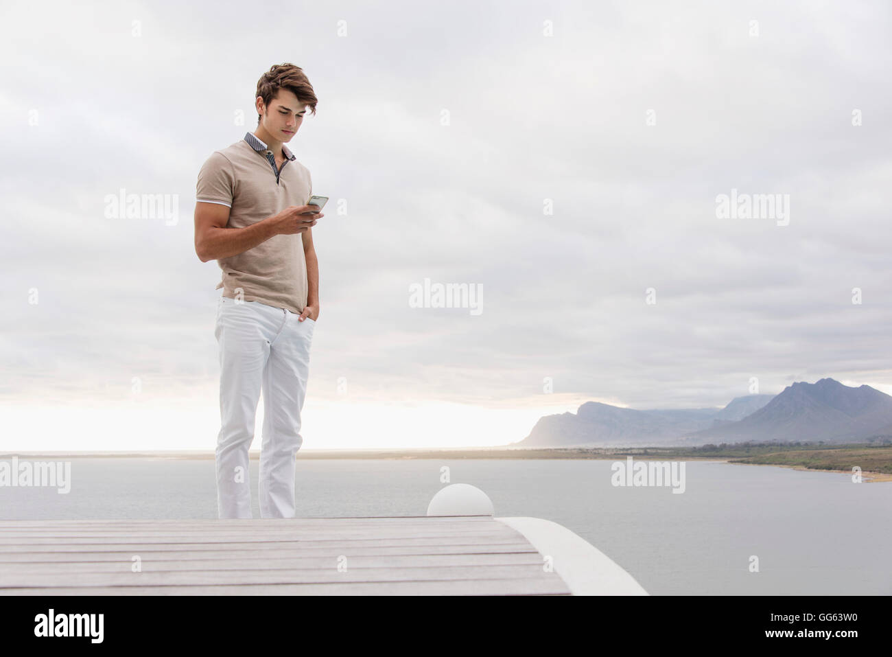 Young man using a smart phone at lakeshore Stock Photo - Alamy