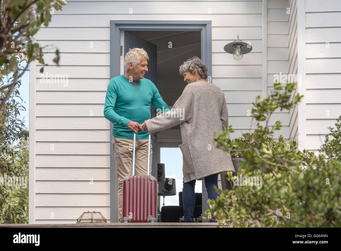 Senior man welcoming woman at doorway Stock Photo - Alamy