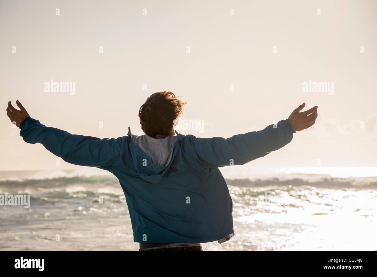 Happy young man with arm outstretched on beach Stock Photo - Alamy