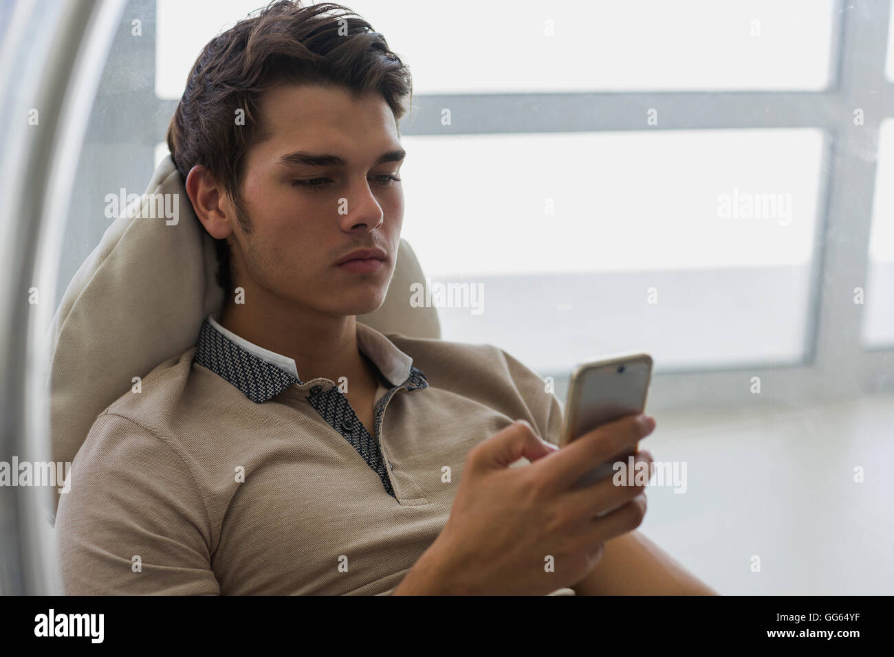 Man sitting in a chair using a smart phone Stock Photo - Alamy