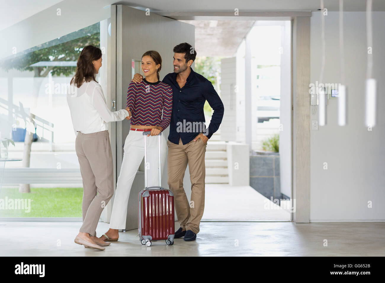 Woman welcoming her friends at doorway Stock Photo - Alamy