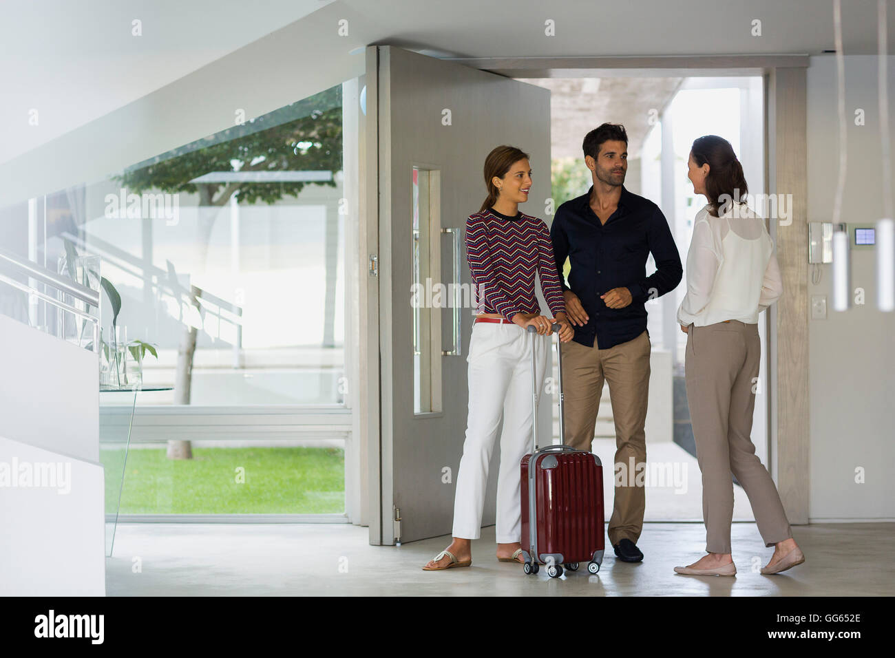 Woman welcoming her friends at doorway Stock Photo - Alamy