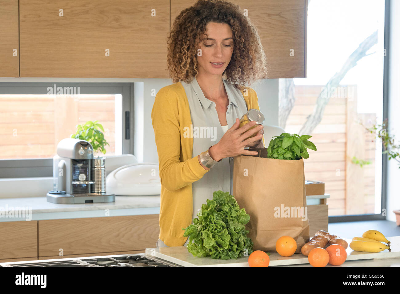 Woman taking out food from a paper bag in the kitchen Stock Photo - Alamy