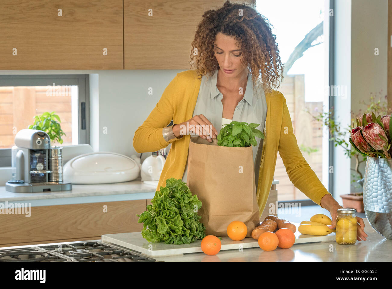 Woman taking out food from a paper bag in the kitchen Stock Photo - Alamy