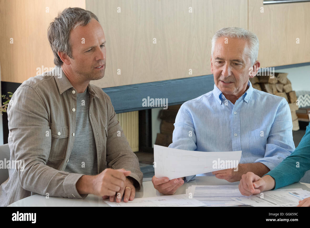 Senior man doing paperwork with son in a living room Stock Photo - Alamy
