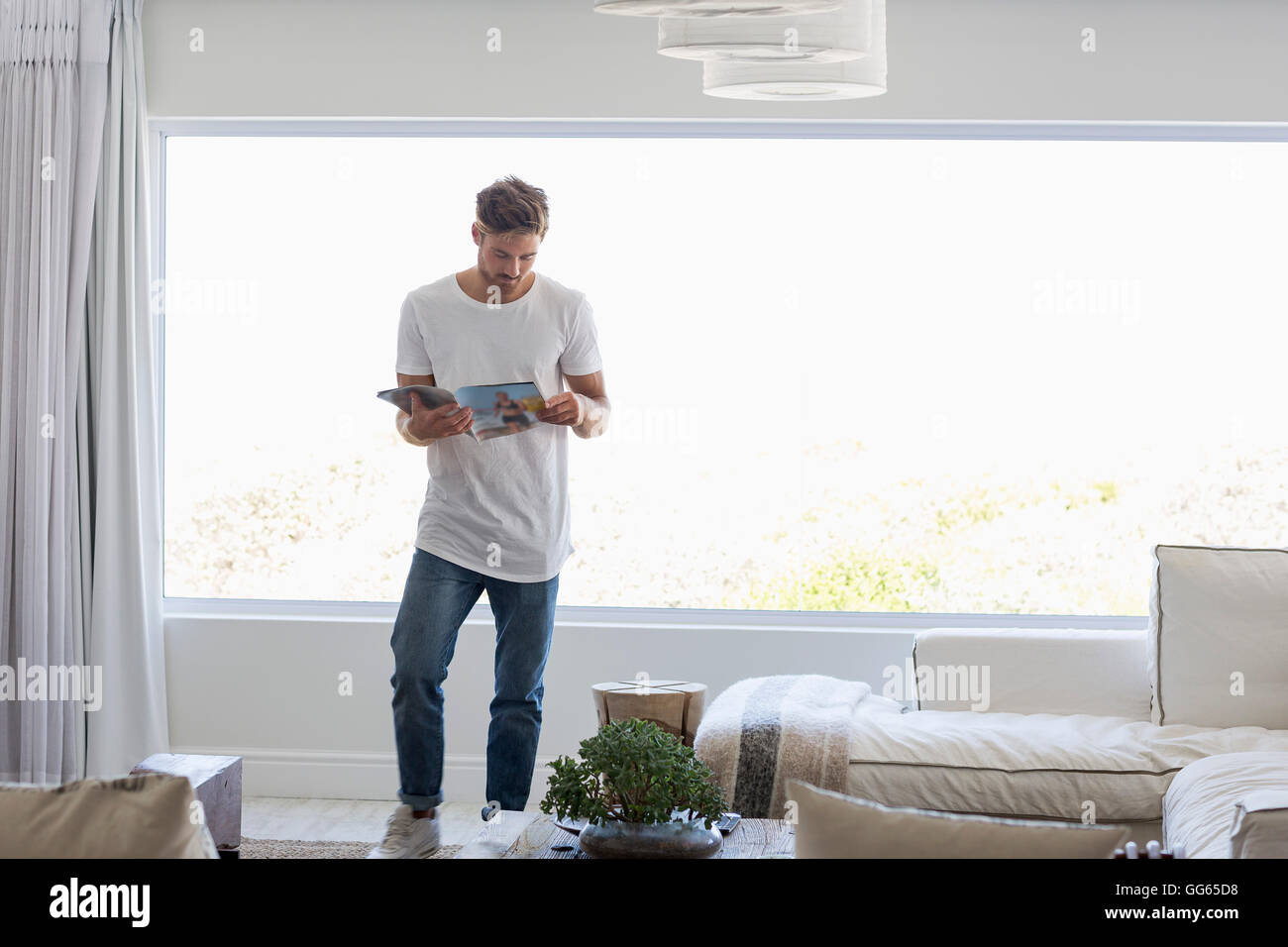 Young man reading a magazine in living room at home Stock Photo - Alamy