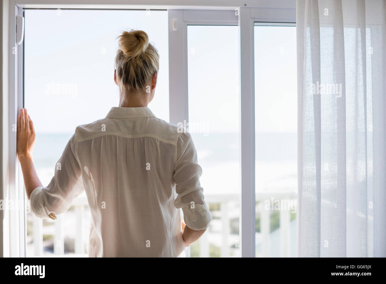 Young woman standing by window at home Stock Photo - Alamy