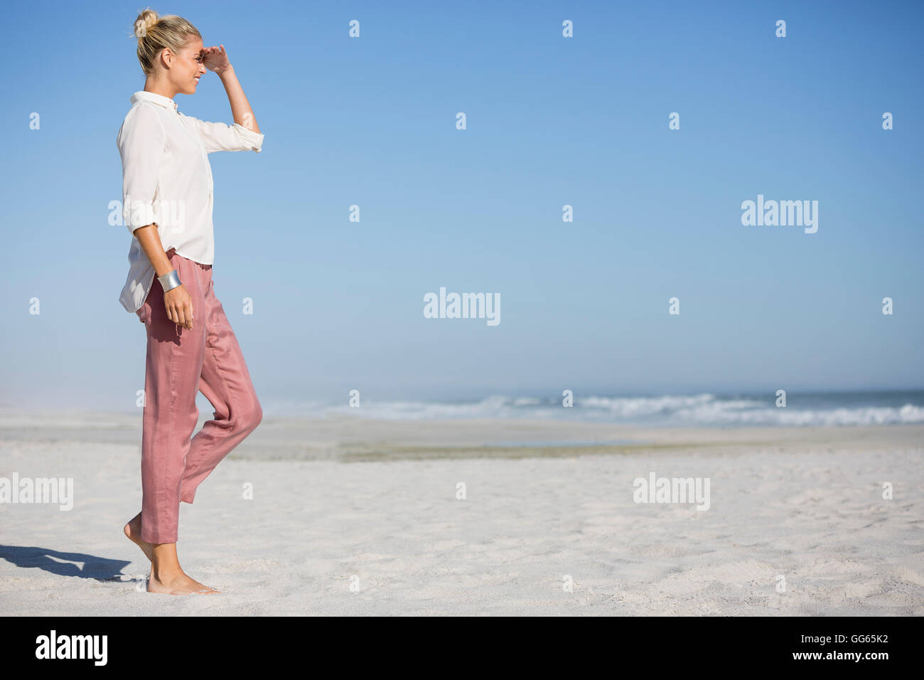 Beautiful young woman walking on sunny beach Stock Photo - Alamy