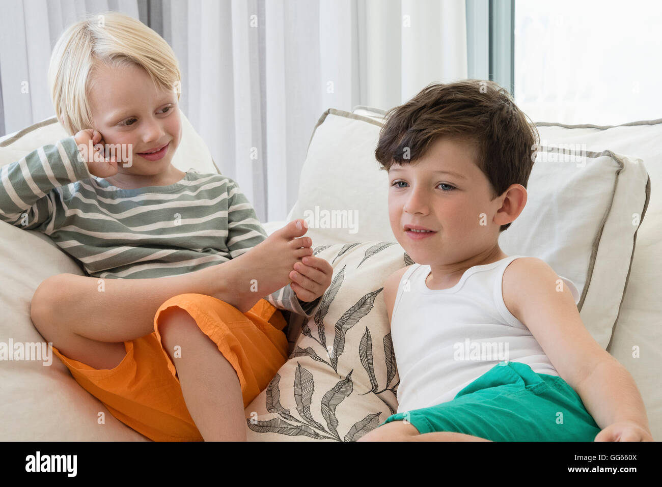 Two happy boys sitting on couch in living room Stock Photo - Alamy