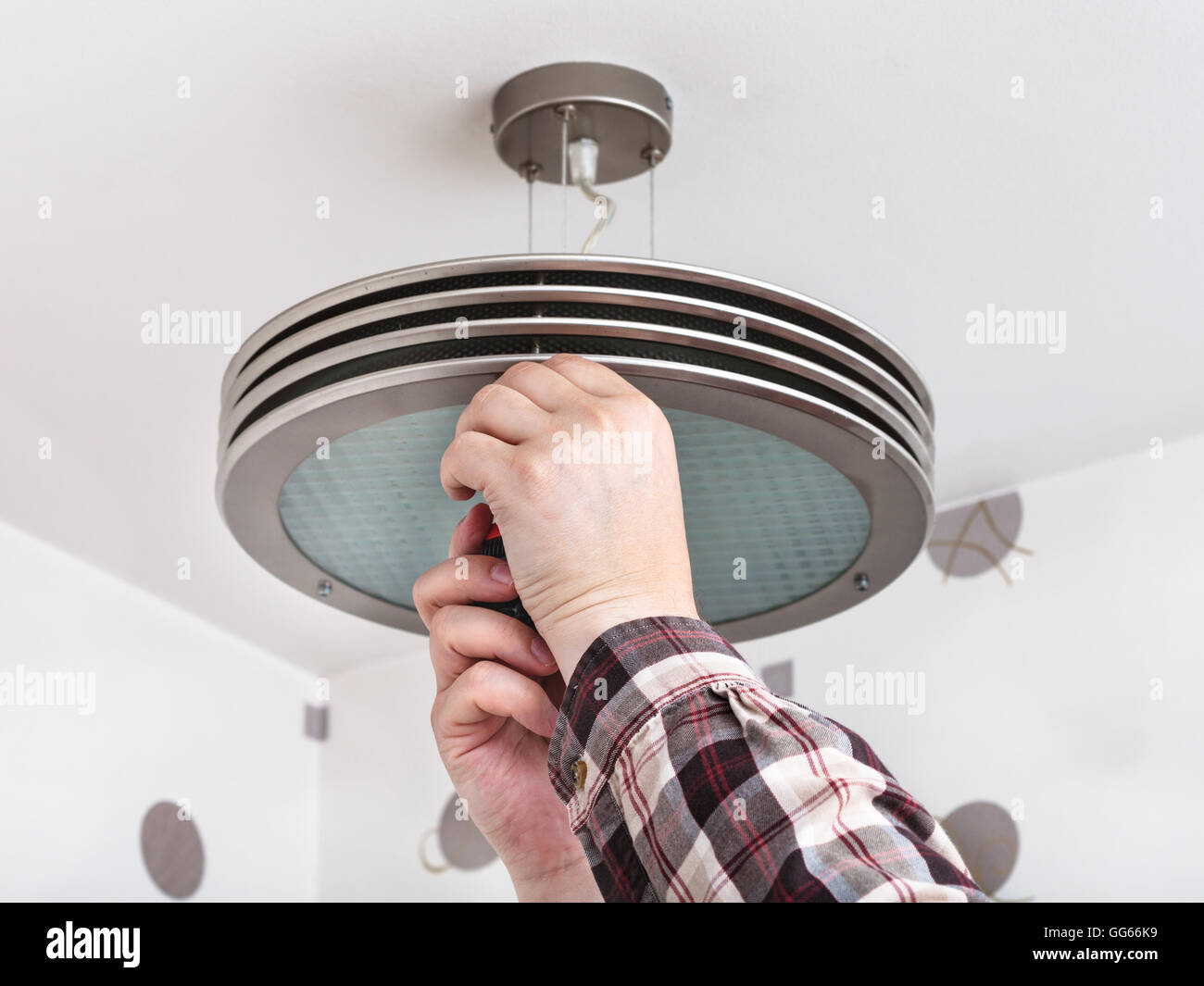 Electrician fixes round ceiling light in room Stock Photo - Alamy