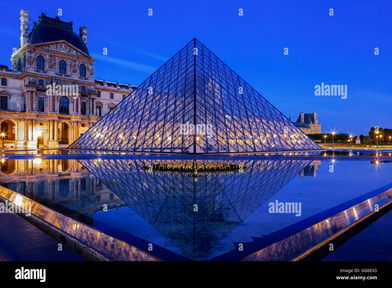The Louvre Pyramid and Palace reflected in a still pool within the ...