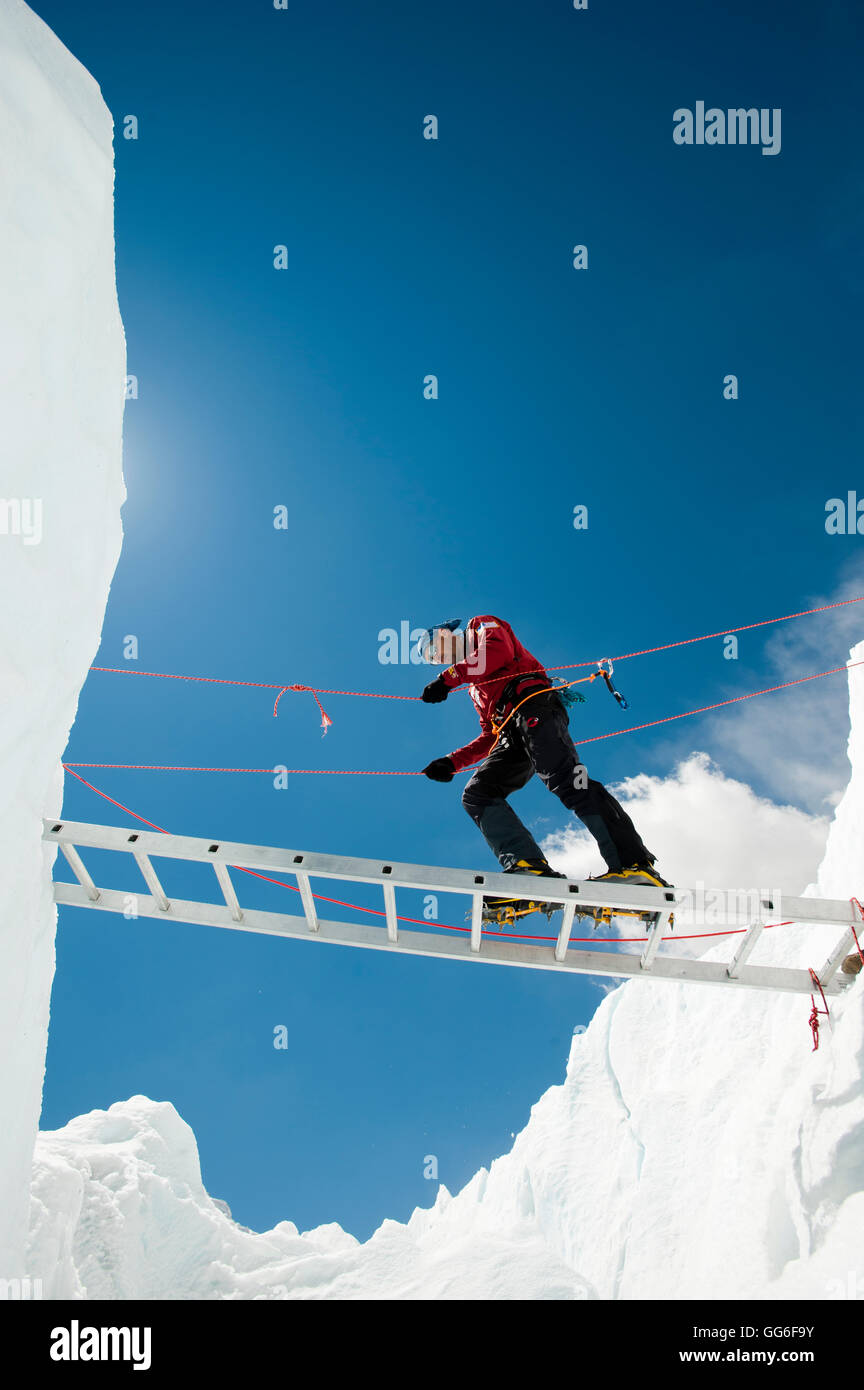 A climber makes his way across a crevasse using a temporary ladder ...