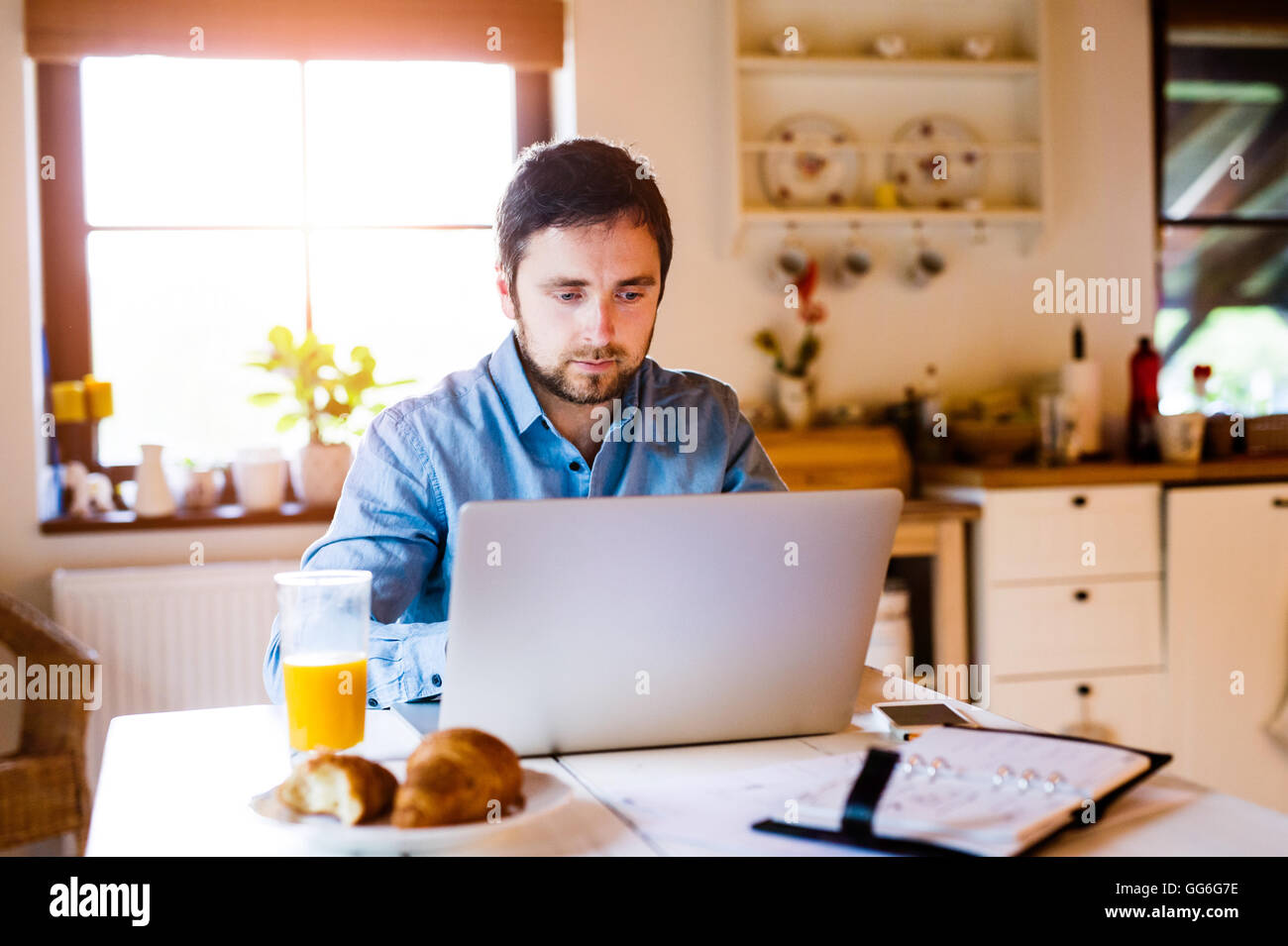 Man sitting at desk working from home on laptop Stock Photo - Alamy