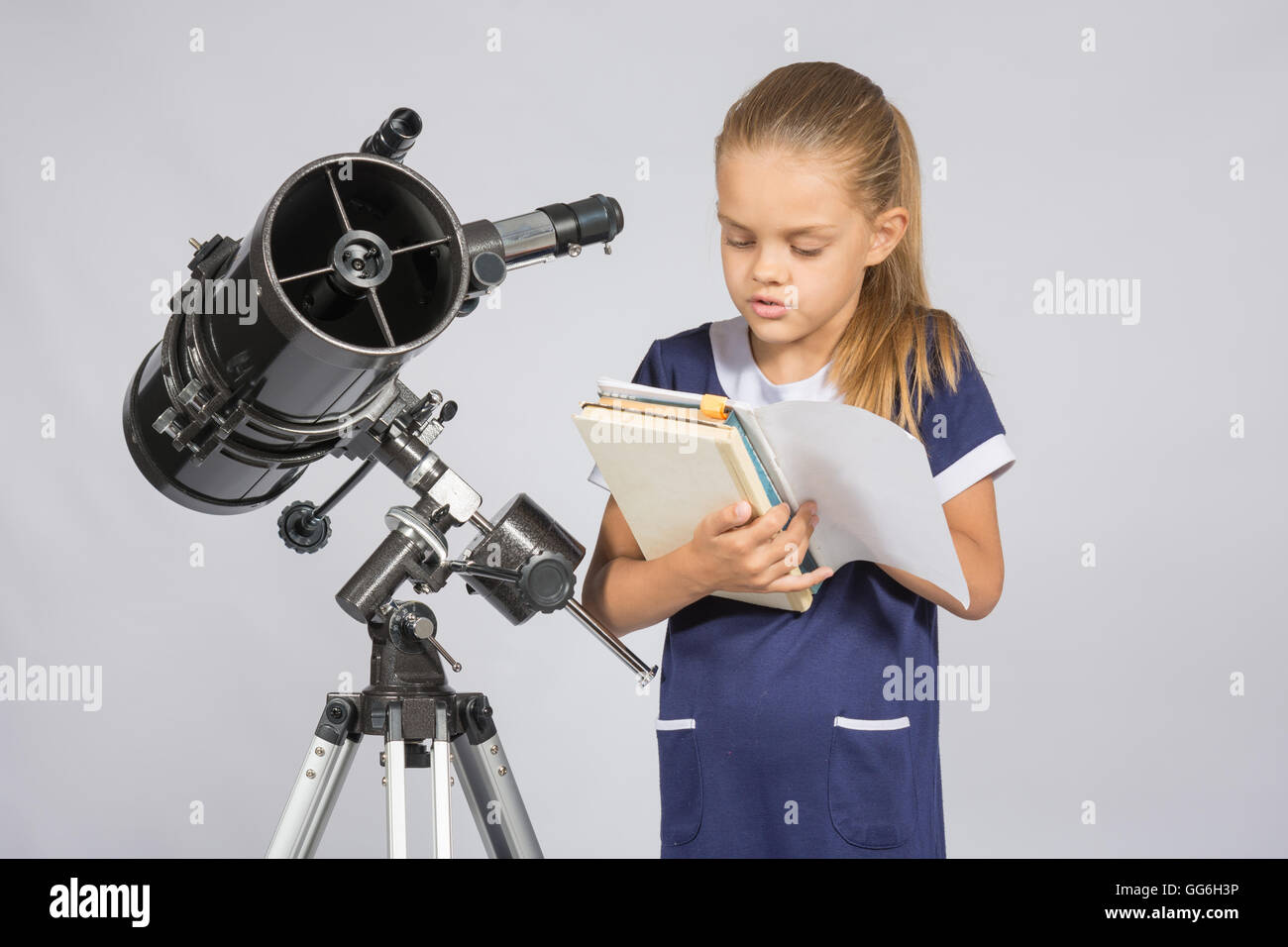 Schoolgirl reading a textbook while standing astronomer at the ...