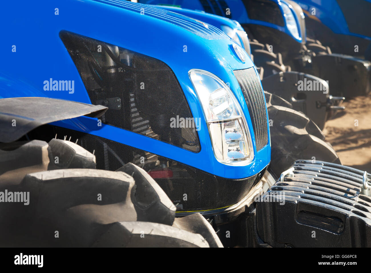 Close up of blue modern tractors on a row Stock Photo - Alamy