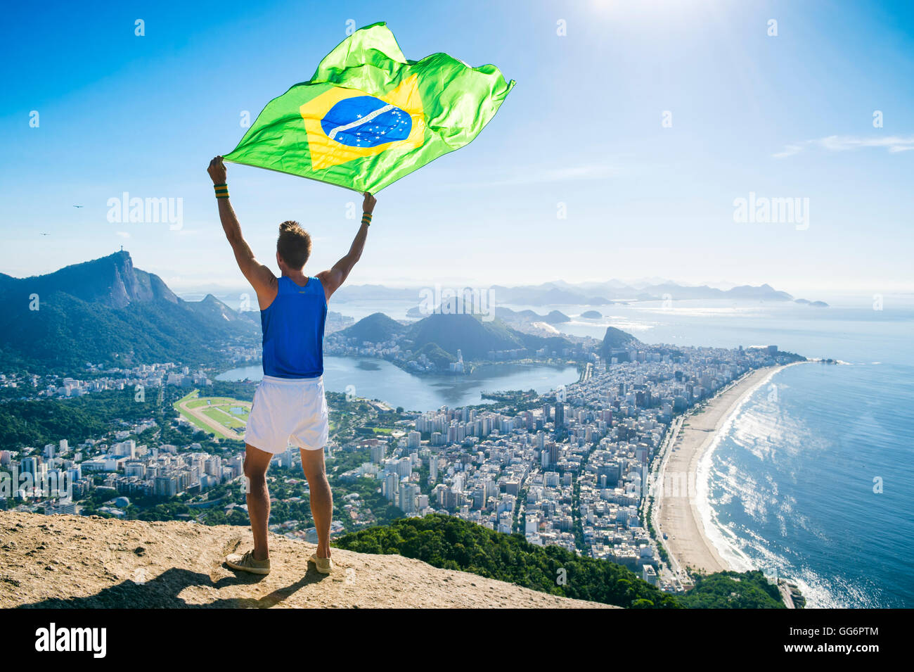 Athlete stands holding a Brazilian flag at a bright overlook of the ...